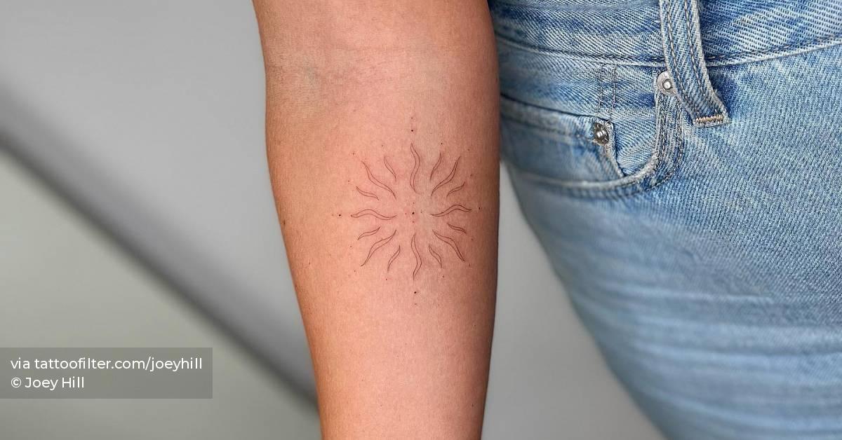 Fine line sun tattoo located on the inner forearm.