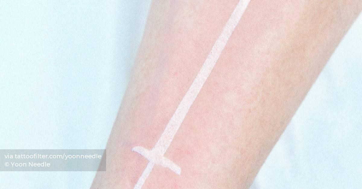 Hand poked white sword tattoo located on the wrist.