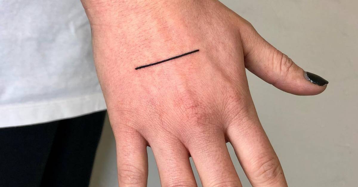 Small line tattooed on the hand, minimalistic style.