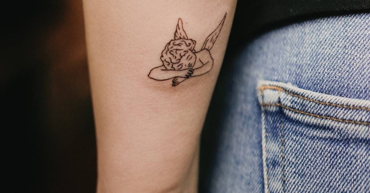Fine line cherub tattoo located on the forearm.