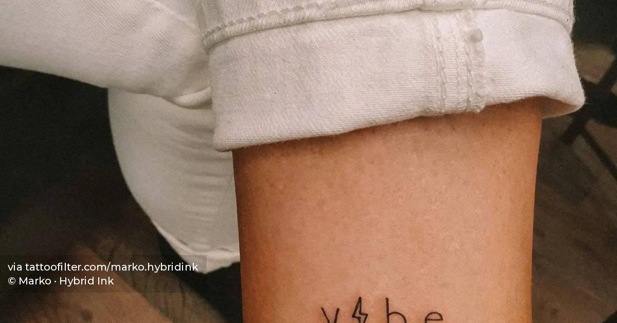 Word "vibe' with a little lightning bolt tattooed on