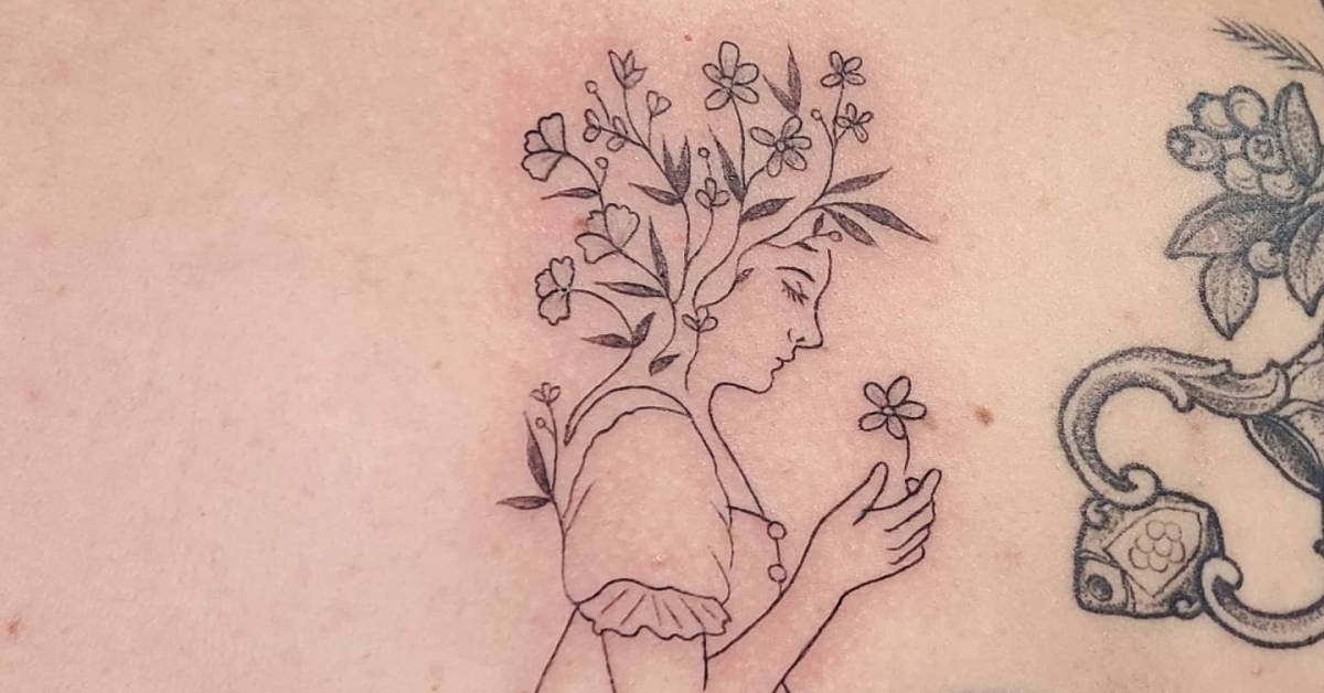 Fine line flower head woman tattoo done on the shoulder