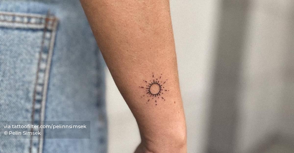 Fine line sun tattooed on the wrist.