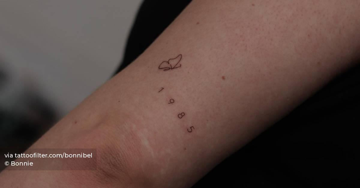"1985" and little butterfly tattooe on the tricep.