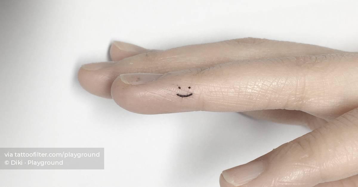Smiley tattoo done on the finger, minimalistic style.