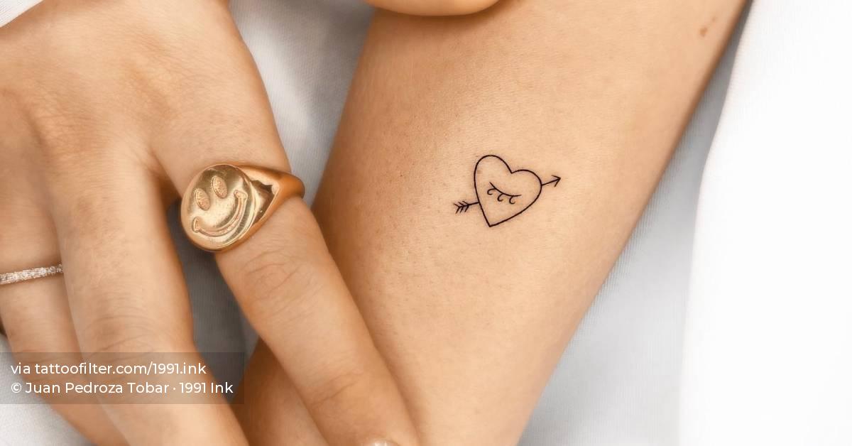 Minimalistic style heart and arrow tattoo located on