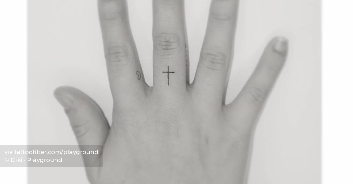 Tattoo of a tiny cross done on the finger, minimalistic