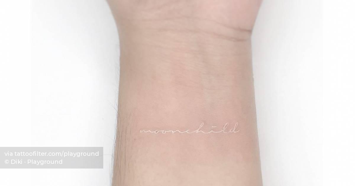 Tattoo of the word "moonchild" in white ink, located on