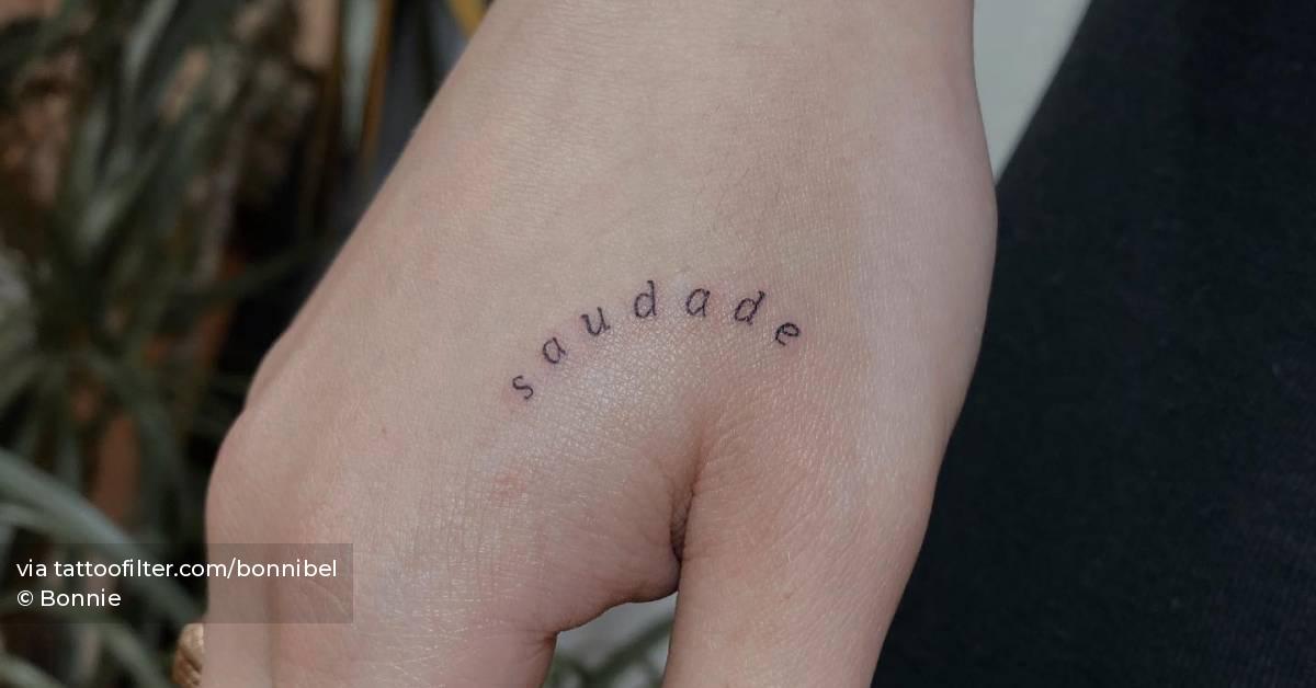 Tatuagem da palavra "saudade" feita na mão.