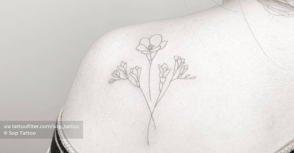 Fine line lily flowers tattooed on the shoulder blade.
