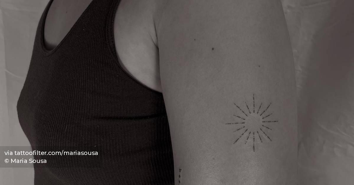 Fine line sun tattoo located on the upper arm.