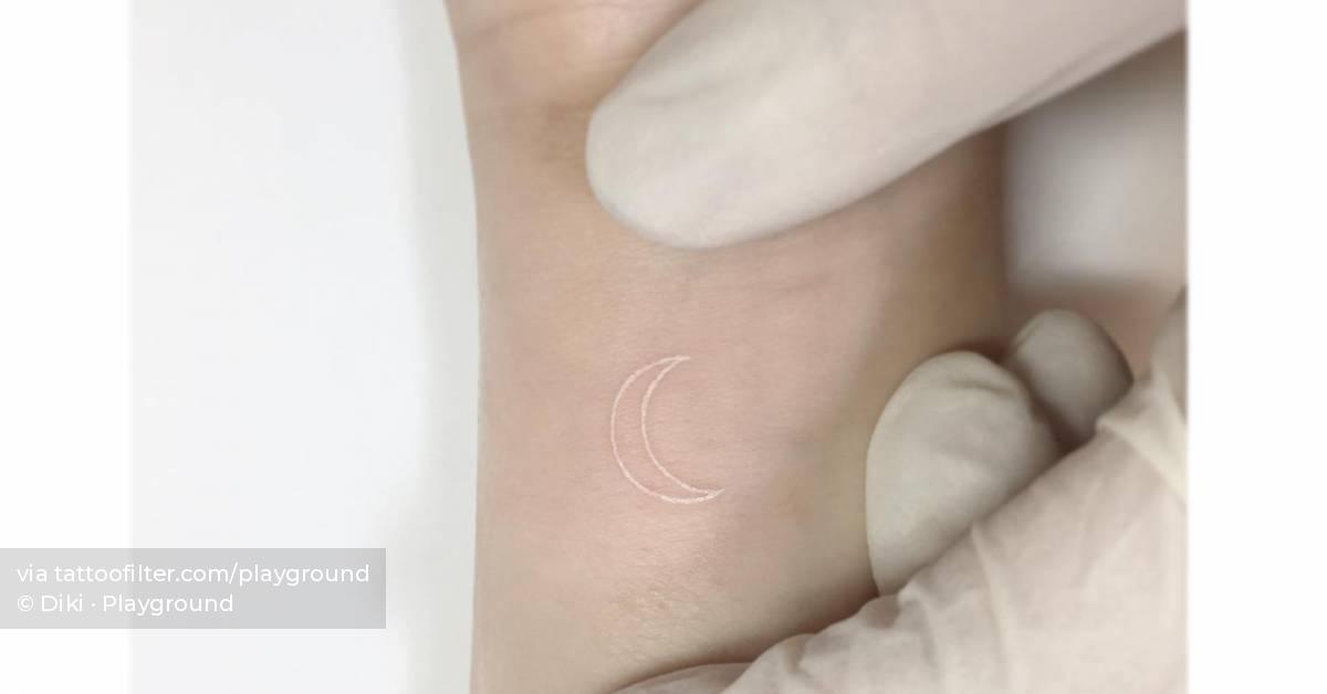 Crescent moon in white ink tattooed on the wrist.