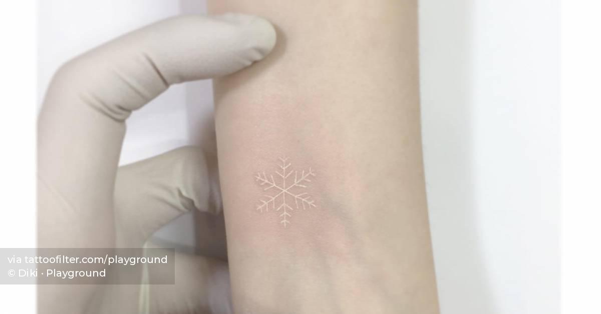 Minimalistic style white snowflake tattoo placed on the