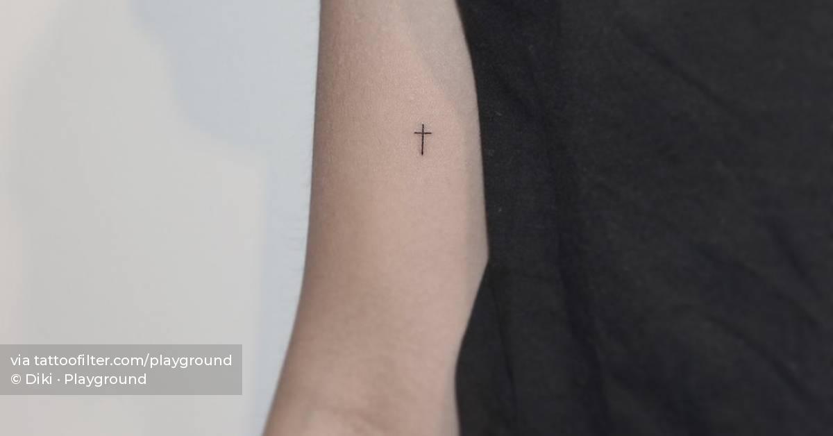 Mini cross tattoo located on the bicep.