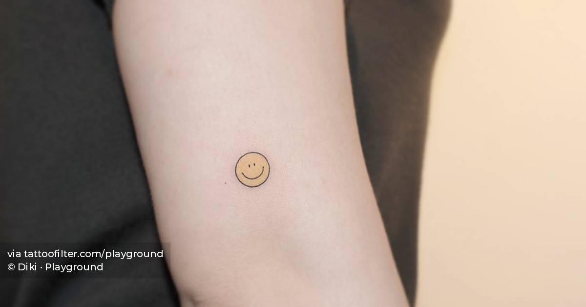 Small smiley face tattooed on the upper arm.