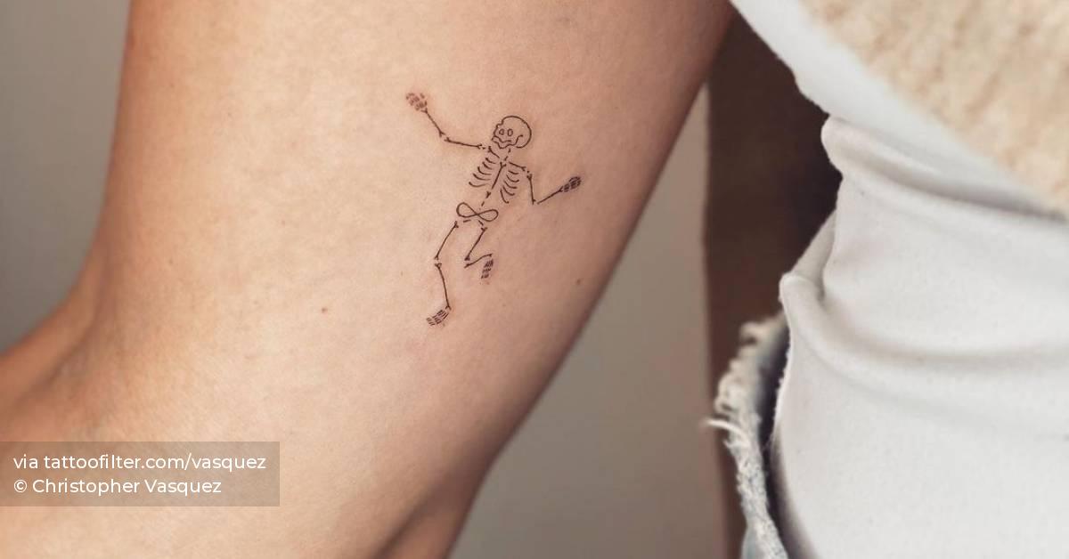 Fine line dancing skeleton tattoo on the inner arm.