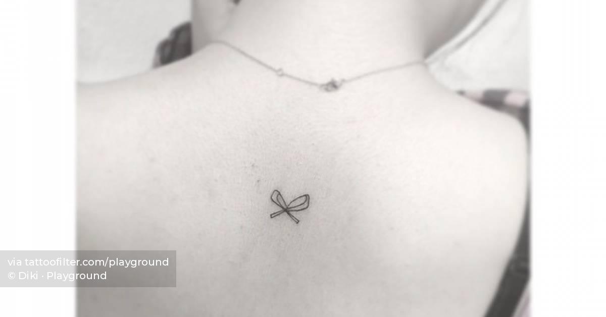 Fine line ribbon tattoo located on the upper back.