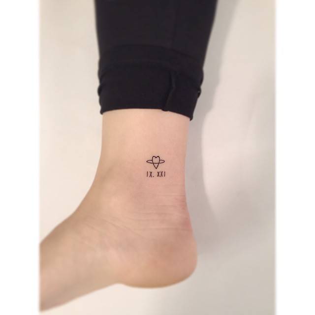 Saturn Heart And Roman Numerals Tattooed On The Ankle 
