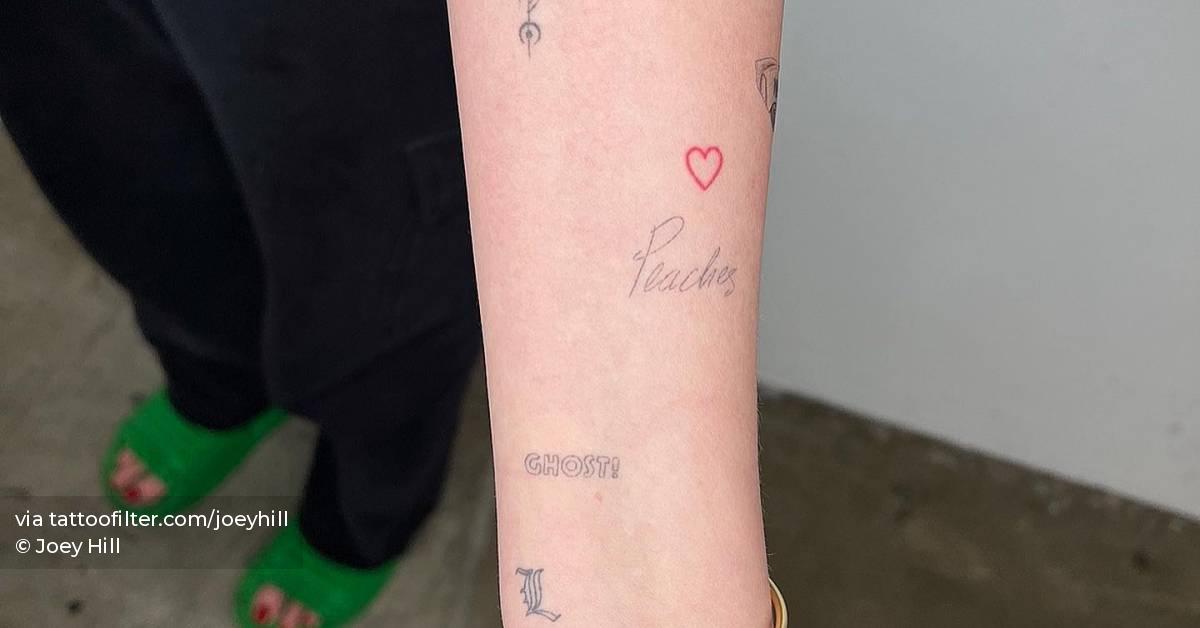 Healed "peaches" and "ghost" lettering tattoo located