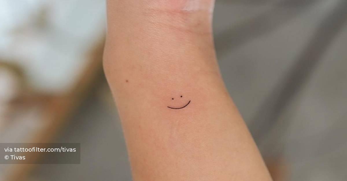 Tiny minimalistic smiley tattoo located on the wrist.