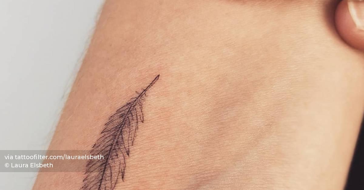 Fine line feather tattoo located on the wrist.