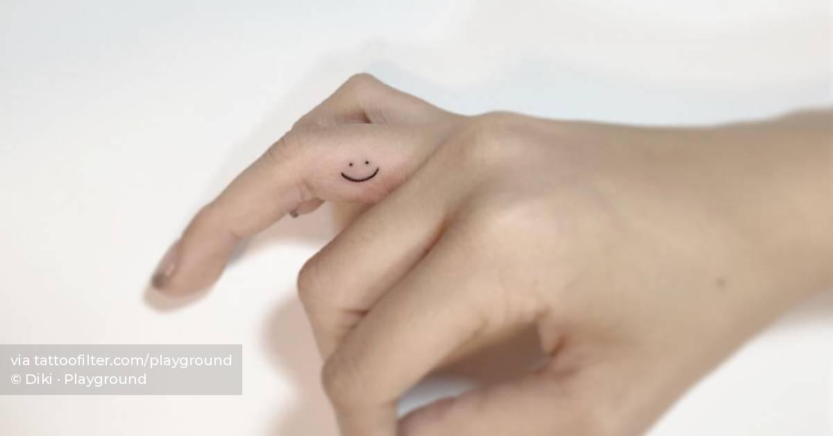 Tiny smiley face tattoo located on the finger.