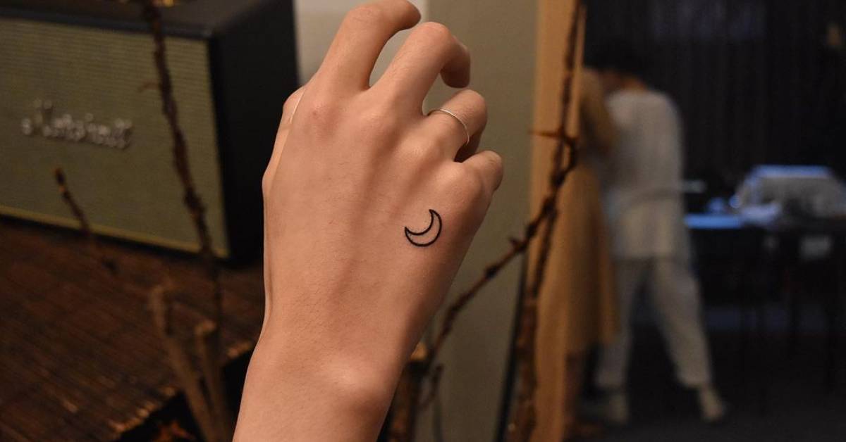 Minimalist crescent moon tattoo on the hand.