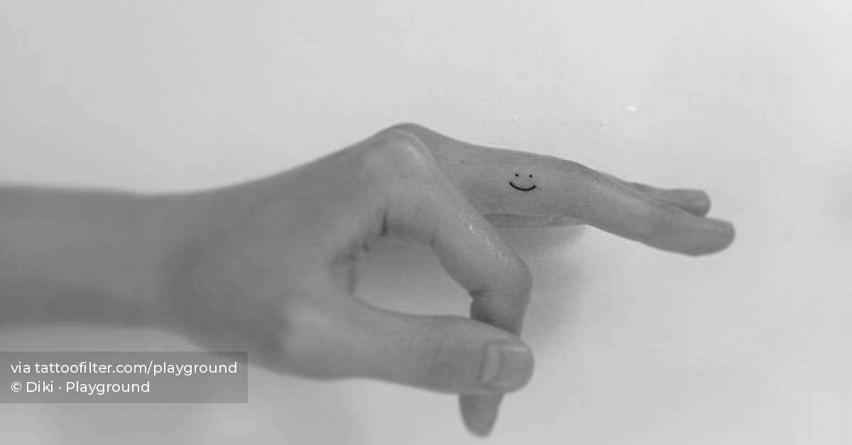 Smiley face tattoo located on the finger, minimalistic