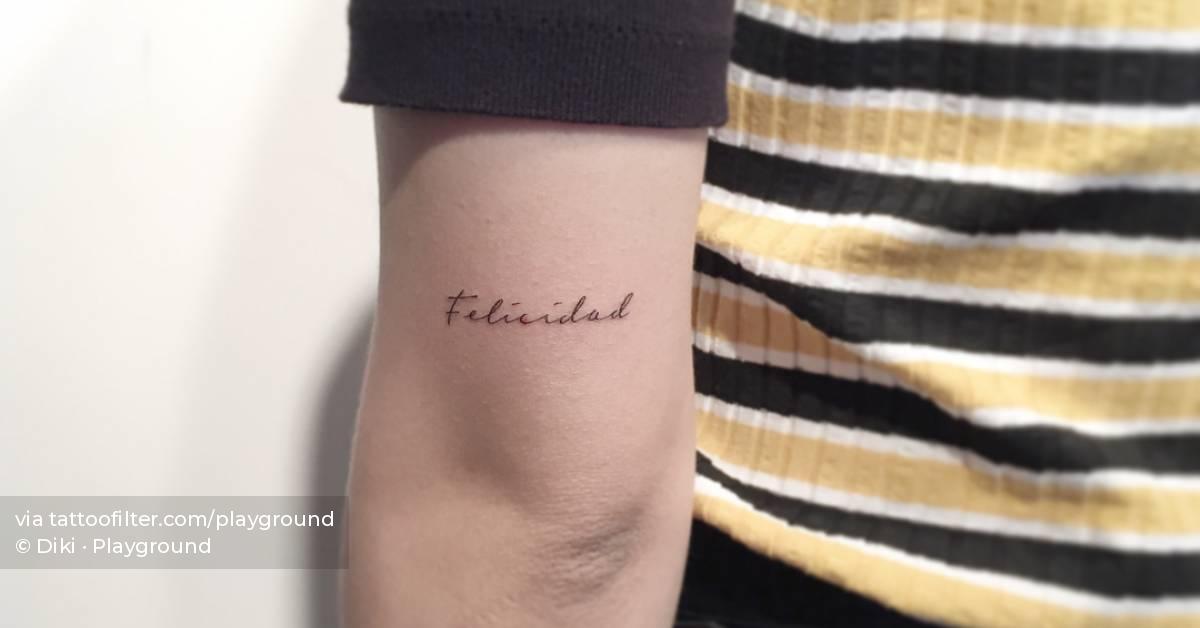 "Felicidad" lettering tattoo placed on the tricep.