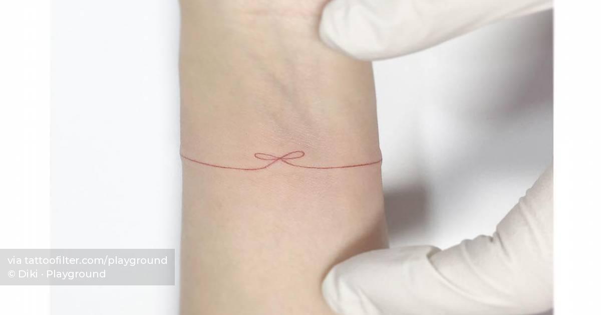 Minimalistic style ribbon wristband tattoo in red ink.