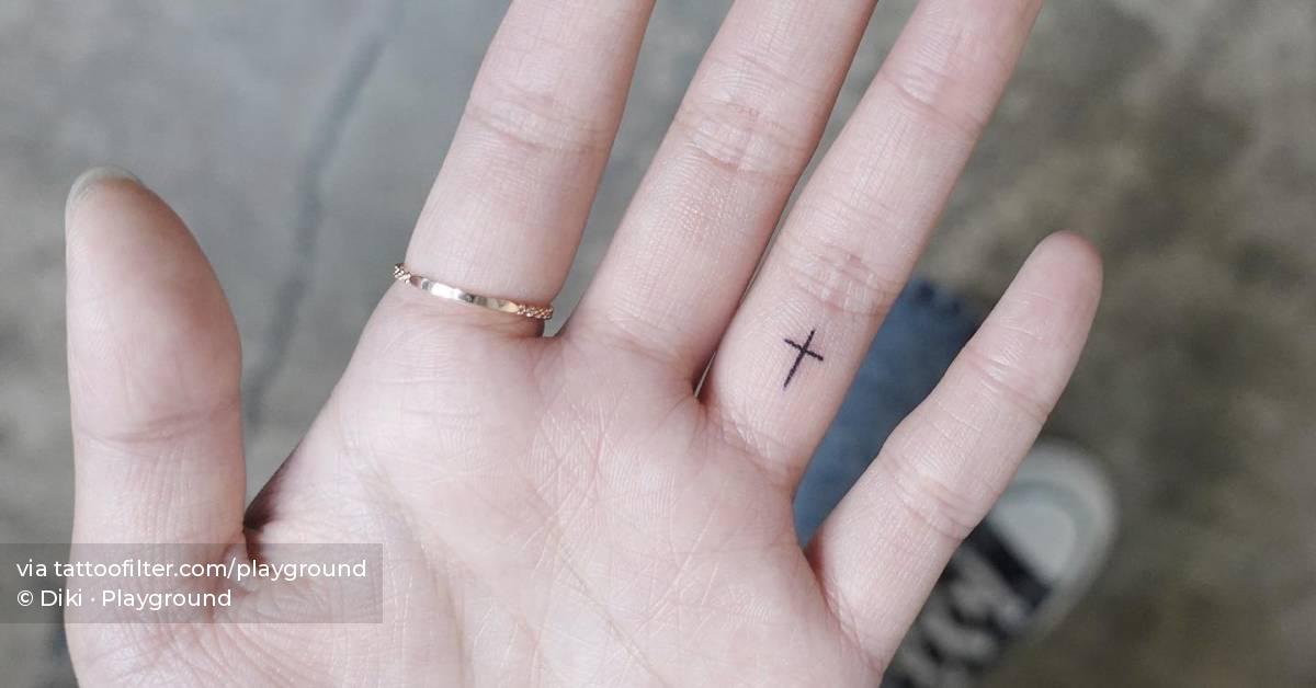 Little cross tattoo done on the finger, minimalistic