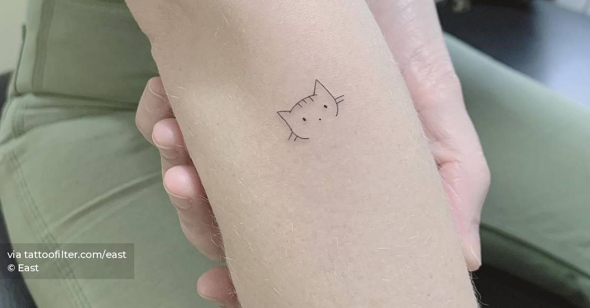 Tiny minimalistic cat portrait tattooed on the forearm.