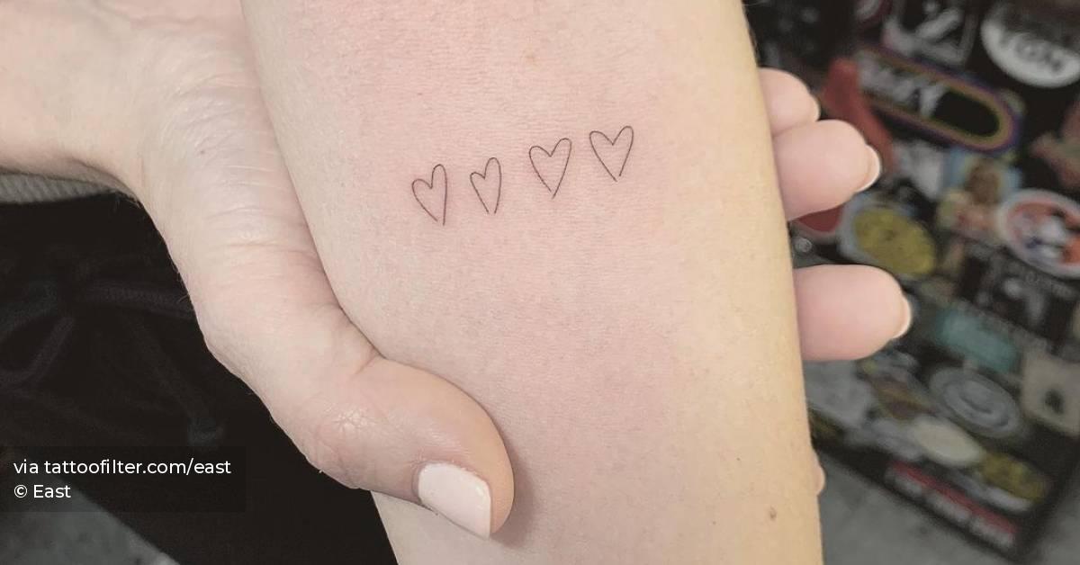Single needle hearts tattooed on the inner forearm.