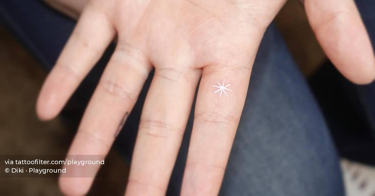 Minimalistic star tattoo done in white ink, located on