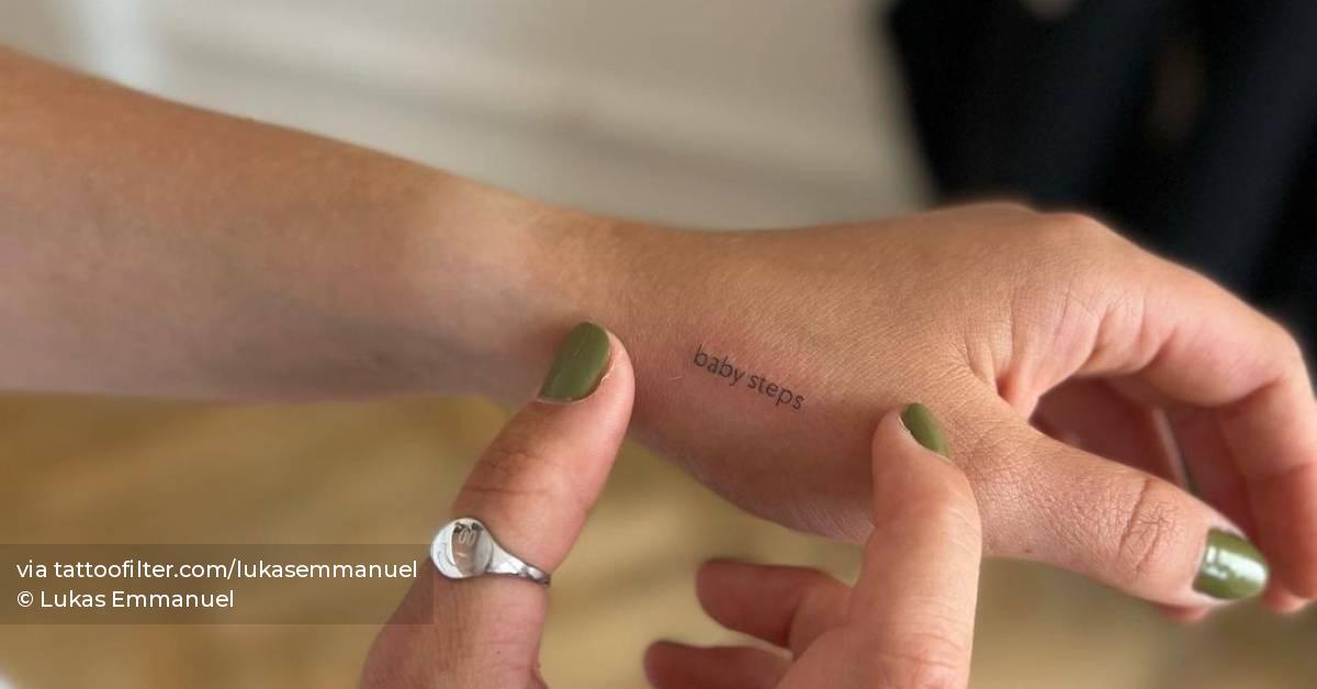 "Baby steps" lettering tattoo located on the hand.