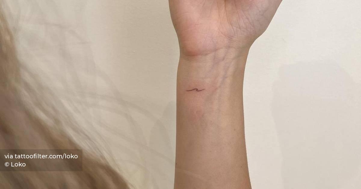 Tiny minimalistic wave tattoo located on the wrist.