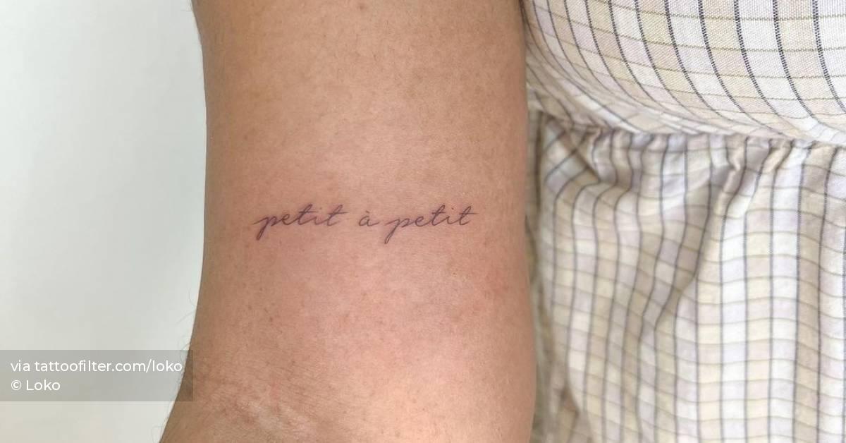 "Petit à petit" lettering tattoo located on the bicep.