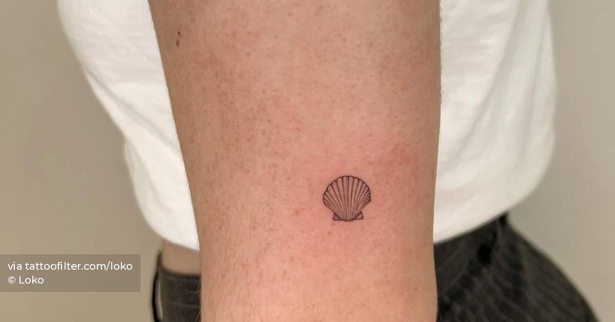 Fine line seashell tattooed on the upper arm.