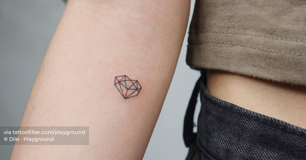 Fine line diamond heart tattooed on the inner forearm.