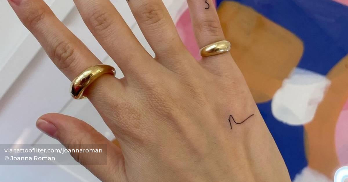 Handwritten letter "N" tattoo located on the hand.