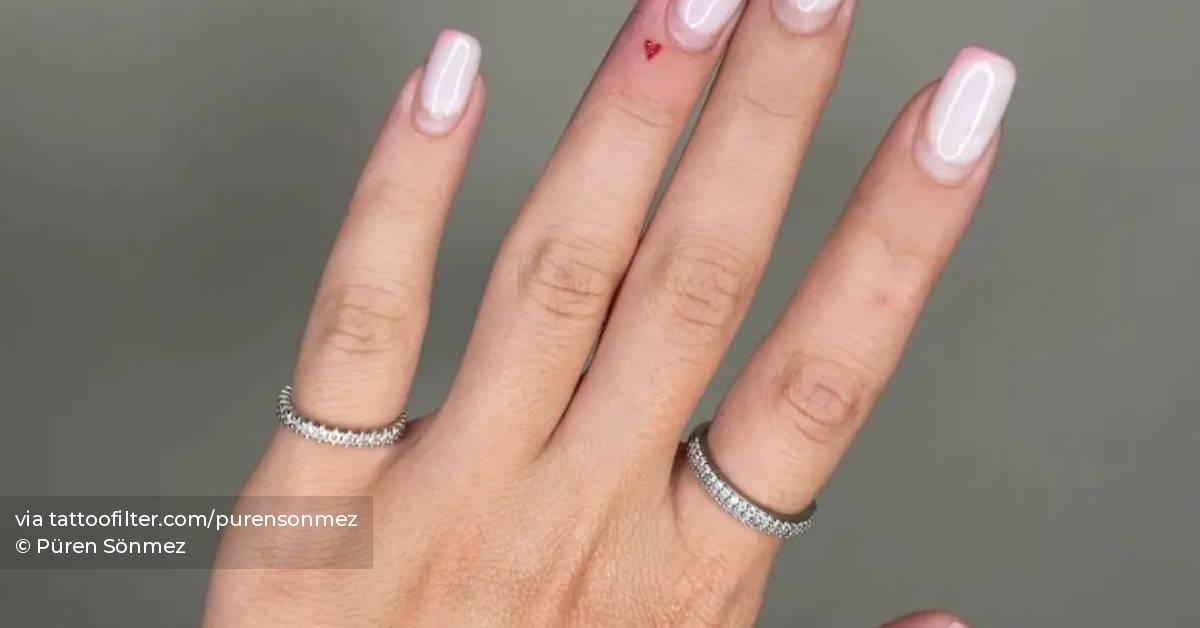 Micro red heart tattoo located on the finger.