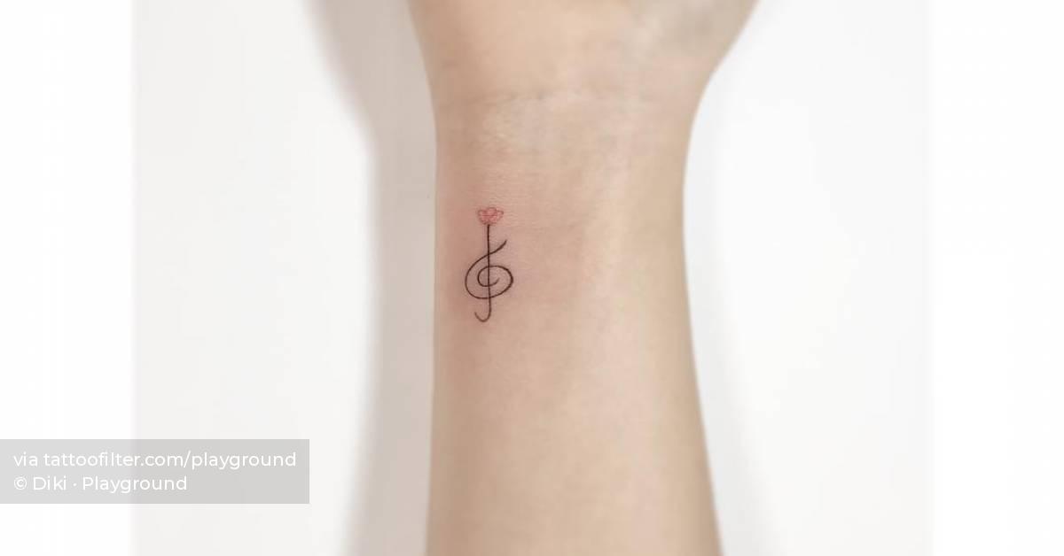 Minimalistic floral treble clef tattoo located on the