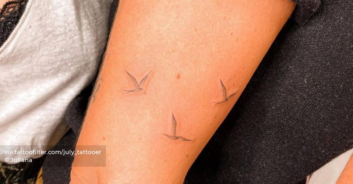 Fine line flying birds tattoo on the upper arm.