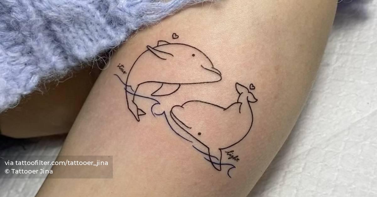 Fine line dolphin tattoo on the upper arm