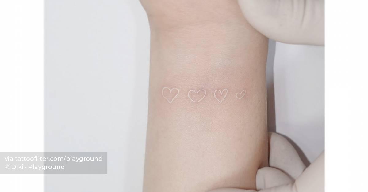 White hearts tattooed on the wrist, minimalistic style.