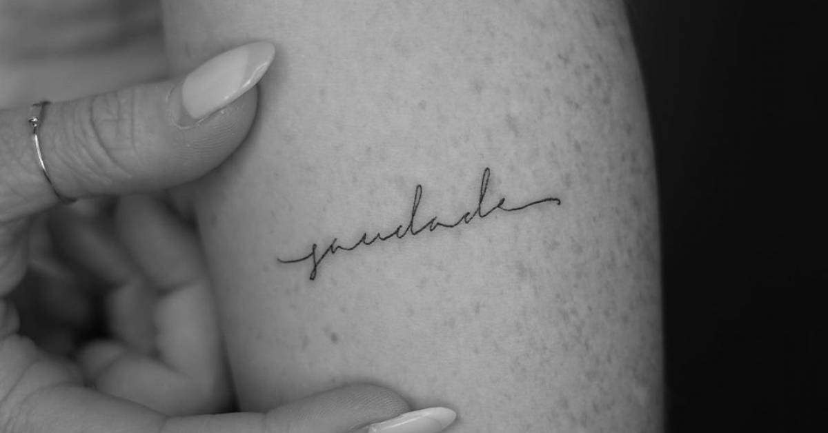 Tattoo of the word "saudade" handwritten on the inner