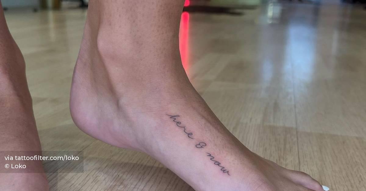 "Here and now" lettering tattoo done on the foot.