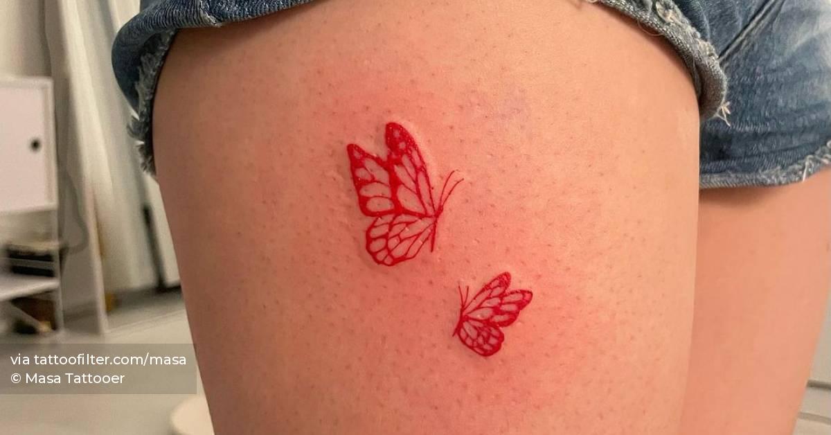 Red butterfly couple tattooed on the thigh.