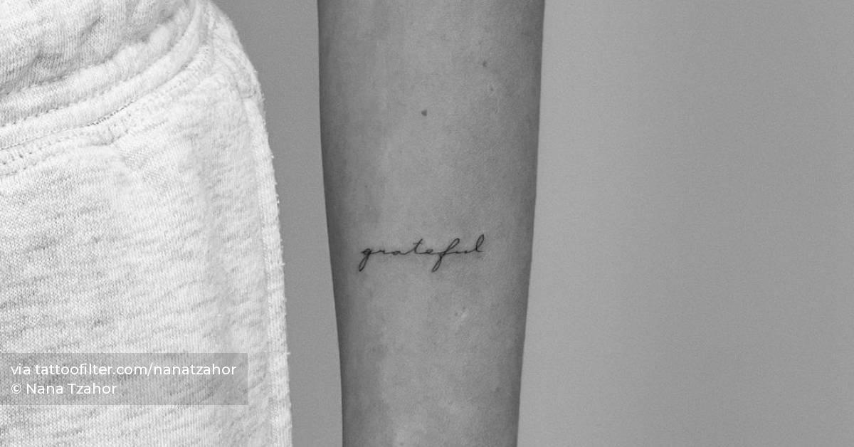 Tattoo of the word "grateful" handwritten on the