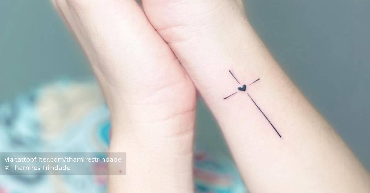 Minimalistic cross and heart tattoo located on the